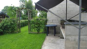 Uma área de pátio com mesa, cadeiras, uma pérgola e um muro de tijolos.