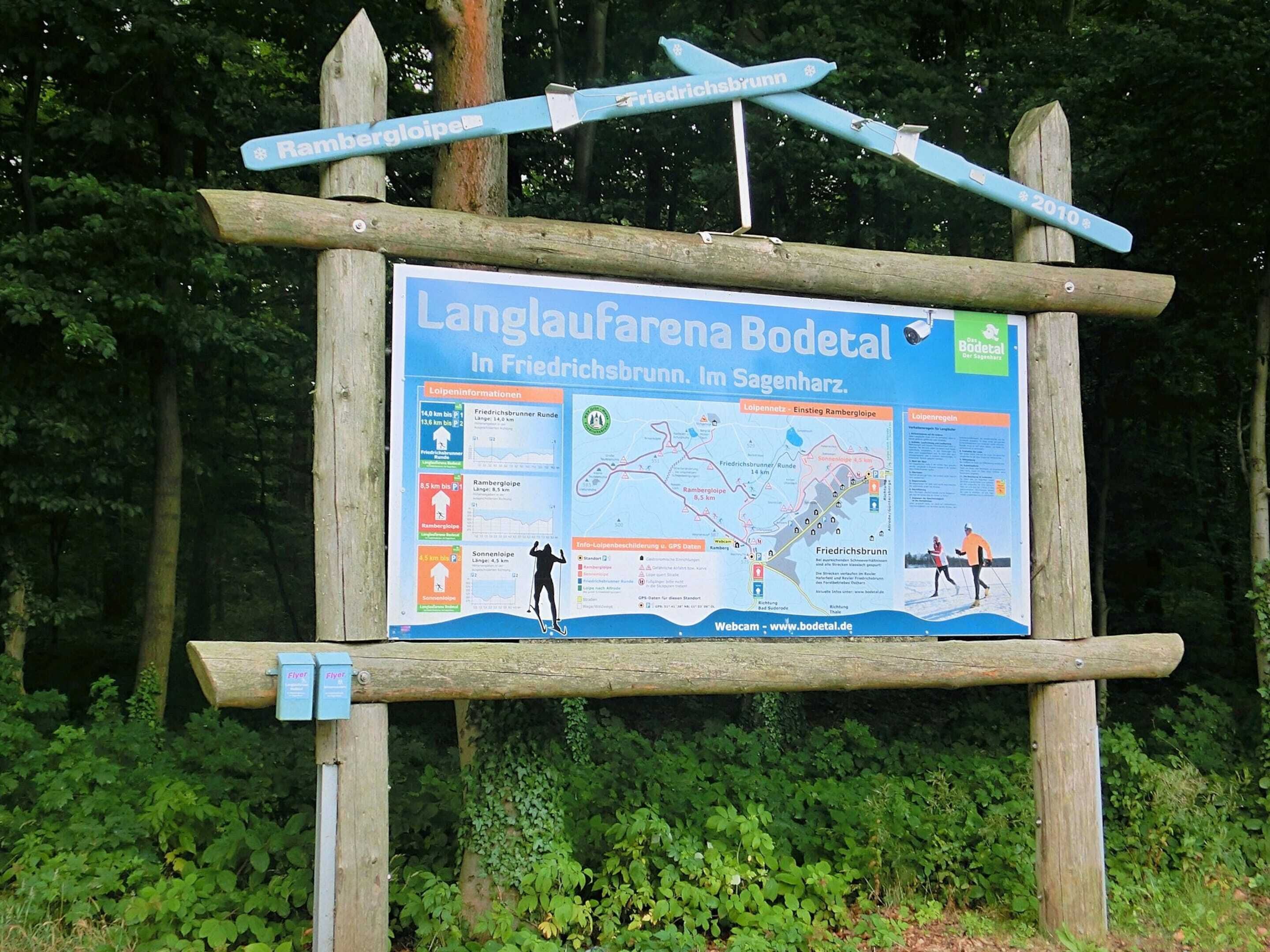 Um sinal de madeira com um mapa e informações sobre Langlaufarena Bodetal em Friedricksbrunn, Im Sagenharz.