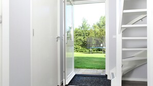 Um corredor com porta de vidro que dá para um quintal com um trampolim.