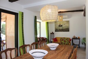 Uma sala de jantar com mesa de madeira, cadeiras e luminária pendente.
