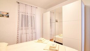 Quarto de hotel com uma cama, um espelho grande e uma janela com cortinas leves.