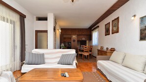 Uma sala de estar aconchegante com um sofá, uma mesa de centro de madeira e um espaço de jantar com mesa e cadeiras.