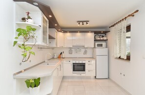Cozinha moderna com armários brancos, forno embutido, micro-ondas e pia.