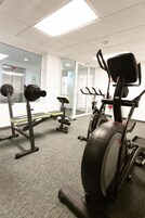 Academia com equipamentos de ginástica, incluindo esteira, bicicleta ergométrica e banco de musculação.