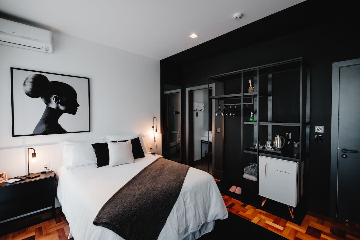 Quarto moderno com uma cama grande, mesas de cabeceira, guarda-roupa e um espelho.