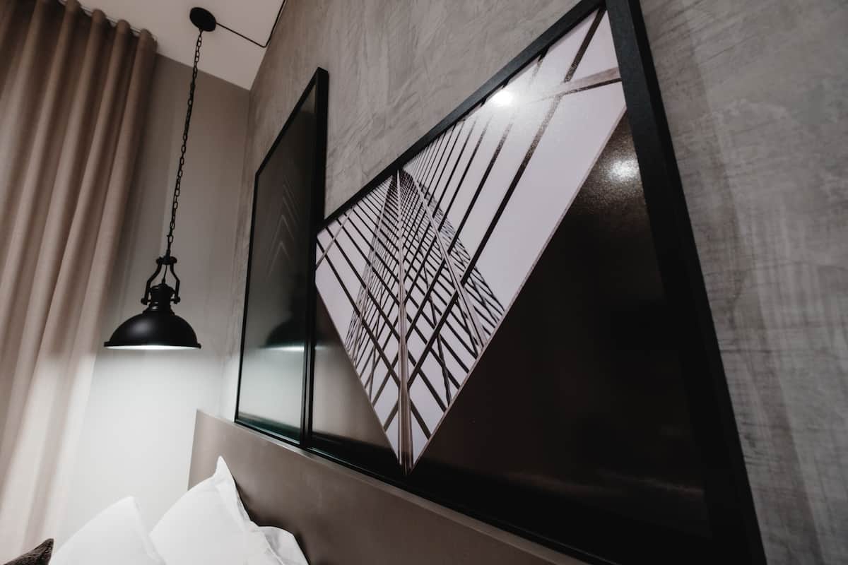Quarto moderno com uma cama, uma luminária pendente e uma grande obra de arte abstrata na parede.