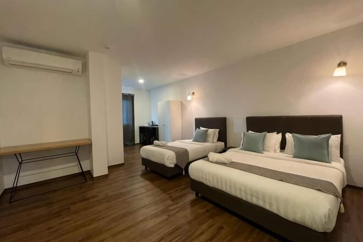 Quarto de hotel com duas camas, uma escrivaninha e um guarda-roupa.