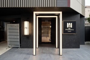 Entrada de um edifício moderno com uma placa que diz 'MONDAY DAIMON'.