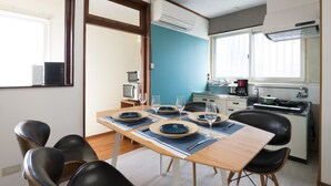 Uma cozinha compacta com área de refeições, equipada com micro-ondas, fogão e mesa de jantar para quatro pessoas.