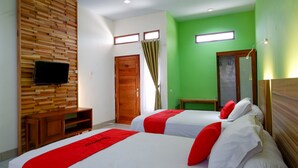 Quarto de hotel com duas camas, cabeceira de madeira, televisão de tela plana, armário de madeira e parede verde decorativa.