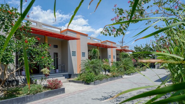 Um edifício moderno com galeria coberta e jardim ajardinado.