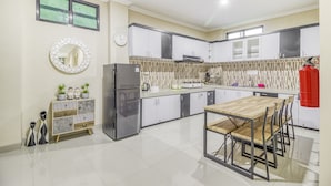 Uma cozinha moderna com uma ilha central, armários brancos e uma área de refeições com mesa e cadeiras de madeira.