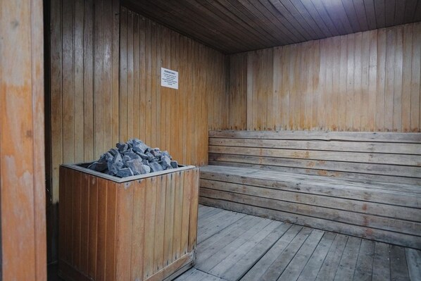Uma sauna com paredes e bancos de madeira, um monte de pedras e um aviso na parede.