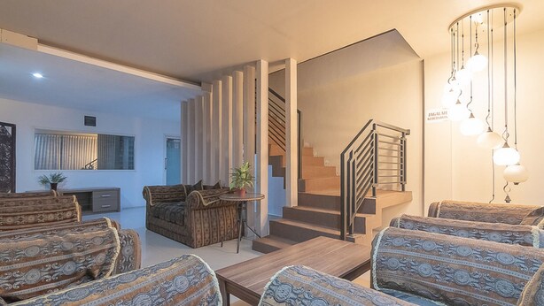 Uma sala de estar moderna com sofás estampados, uma mesa de centro de madeira, uma escada e um lustre.