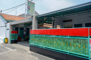 Um edifício com fachada vermelha e verde, telhado em telhas e uma placa.