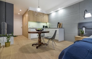 Um espaço de estar moderno e compacto com área de jantar, cozinha compacta e uma cama.