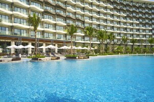 Um hotel com uma grande área de piscina, várias espreguiçadeiras e guarda-sóis.