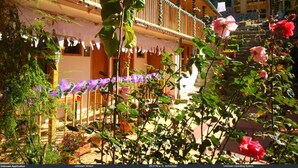 Uma casa de madeira com varanda, rodeada por vegetação e flores.