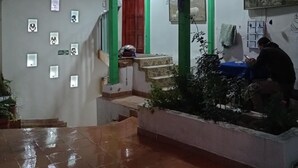 Um edifício com vários níveis, uma escadaria, pilares verdes e piso de azulejos.