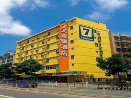 Um hotel 7 Days Inn com vários andares, uma placa laranja bem visível e um céu azul claro.