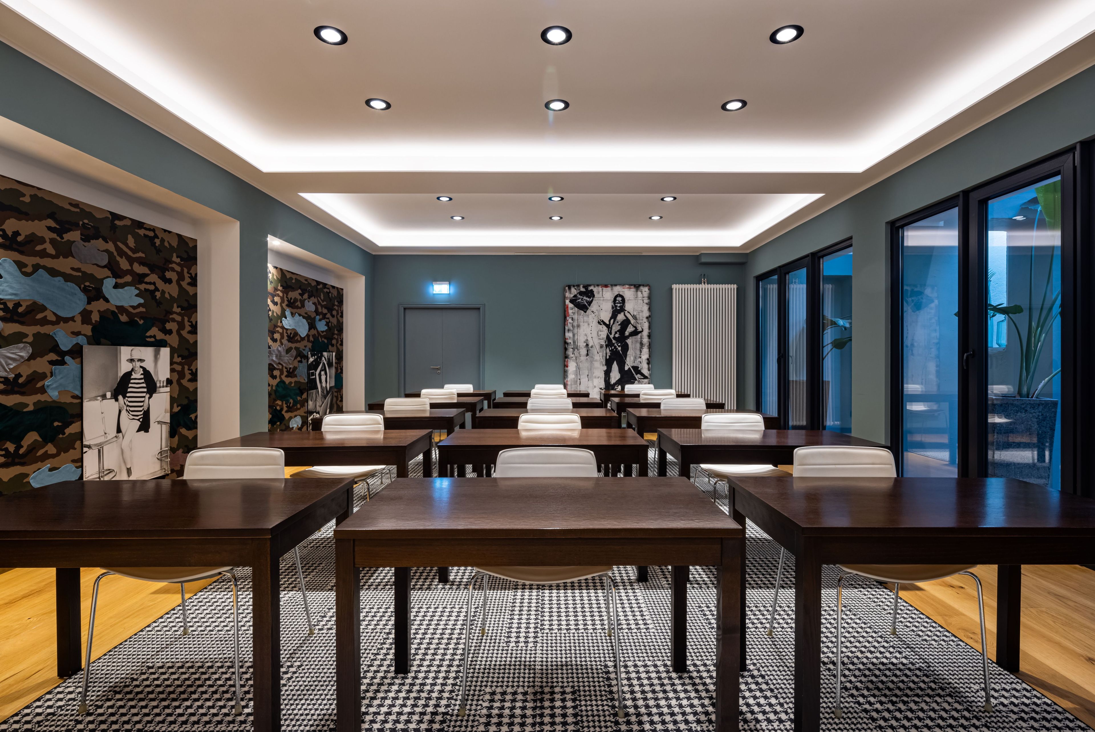 Uma sala de conferências com design moderno, com uma mesa comprida e cadeiras, piso estampado e uma grande janela em um dos lados.