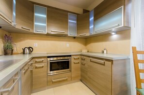 Cozinha moderna com armários de madeira, eletrodomésticos de aço inoxidável e bancada de cor clara.