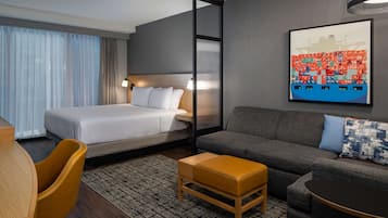 Quarto de hotel com cama, sofá, mesa pequena e cadeira.