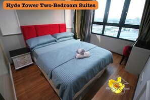 Suíte com dois quartos, cama com cabeceira vermelha, janela grande com vista para a cidade, mesa de cabeceira com gavetas e uma cadeira vermelha pequena.