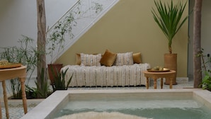 Um espaço interno aconchegante com um sofá-cama, uma piscina pequena e uma área de jantar.