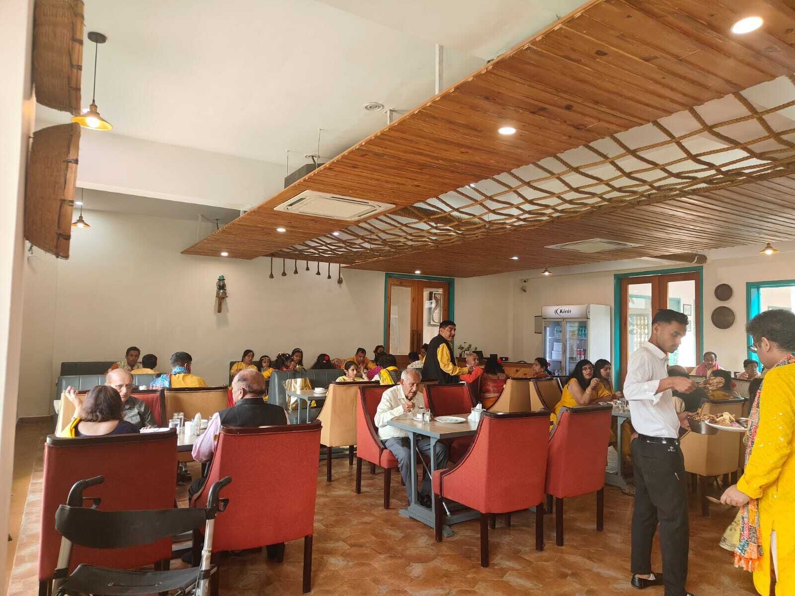 Um restaurante com vigas de madeira no teto, cadeiras vermelhas e pretas, e chão de azulejos.