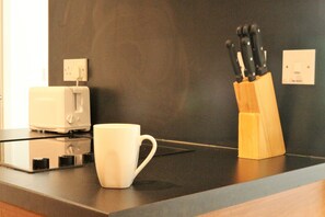 Uma bancada de cozinha com uma caneca branca, uma torradeira e um suporte para facas.