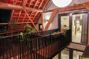 Interior moderno com teto de madeira, varanda com grades pretas e um quarto com a placa 'twa'.