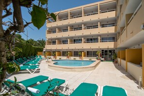 Um hotel com área de piscina, várias varandas e uma fileira de espreguiçadeiras.