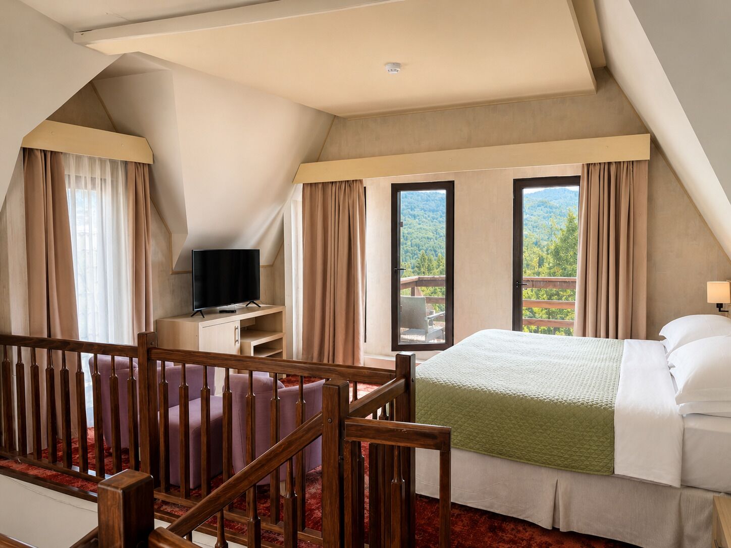 Quarto de hotel com cama, televisão e varanda com vista para a floresta.