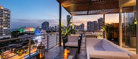 Terraço no telhado com área de estar externa, vista do horizonte da cidade e pérgola de madeira.