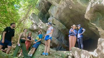 Um grupo de pessoas em terreno rochoso com a entrada de uma caverna.