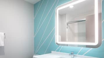 Um banheiro moderno com pia branca, um espelho grande com iluminação LED e parede com padrão azul-turquesa.