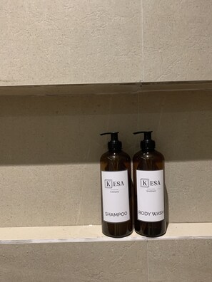 Duas garrafas de shampoo e hidratante corporal KESA em uma prateleira.