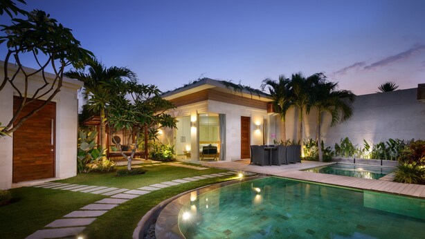 Uma casa moderna com piscina, um alpendre com móveis de exterior e um jardim bem cuidado.