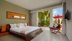 Quarto moderno com cama grande, televisão e vista para um jardim.