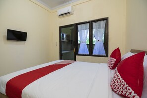 Quarto de hotel com uma cama, televisão e janela com cortinas.