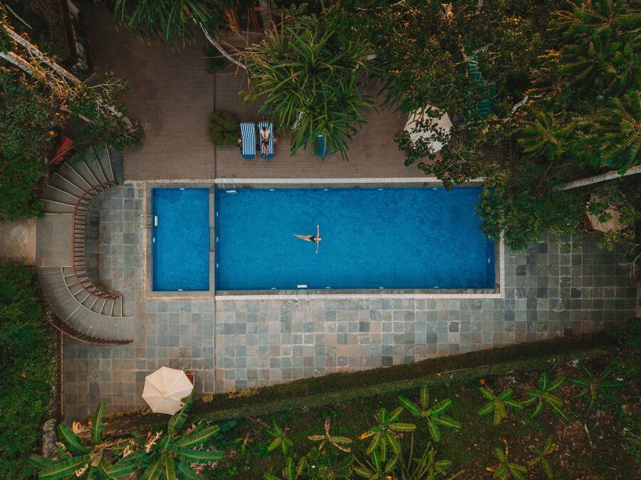 Piscina no terraço com duas espreguiçadeiras e escada que dá para um terraço.