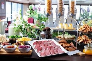 Buffet com diversos alimentos, incluindo carnes, queijos e waffles.