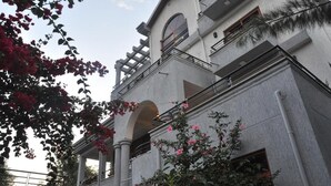 Um edifício com fachada branca, janelas em arco e varandas.