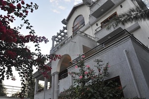 Um edifício com fachada branca, janelas em arco e varandas.