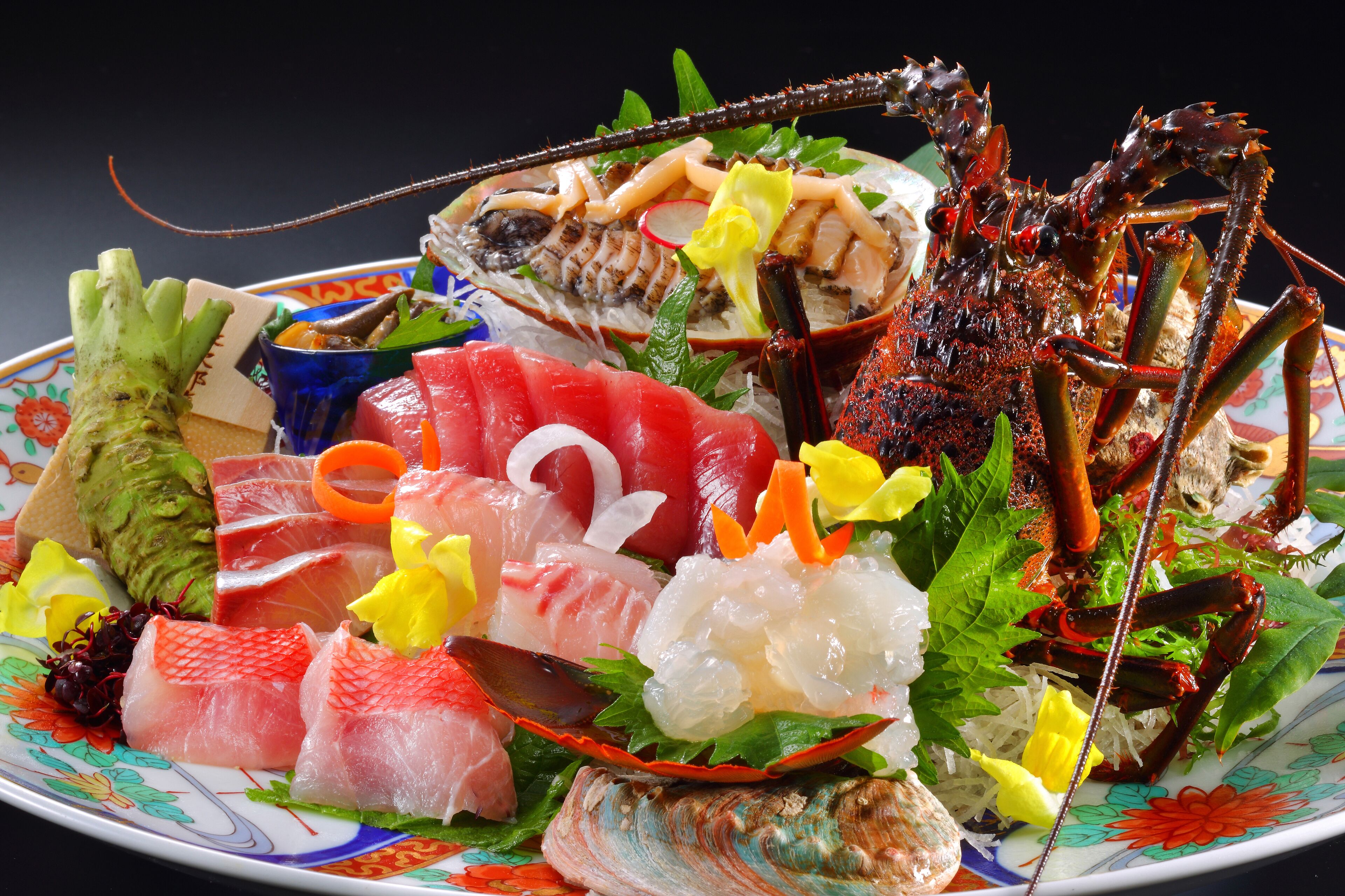 Variedade de frutos do mar, incluindo lagosta, caranguejo e diversos tipos de peixe, dispostos em um prato decorativo.