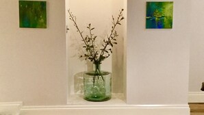 Um quarto com piso de madeira, porta branca e quatro quadros verdes na parede.