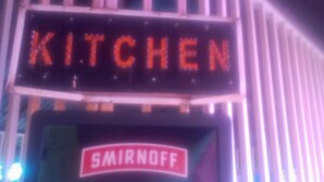 Um ônibus com uma placa na frente que diz "KITCHEN" e "SMIRNOFF".
