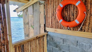 Uma estrutura de madeira com um boi de salvamento pendurado na parede e vista para o mar.