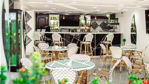 Uma área de bar com mobiliário de vime e uma tela de televisão.